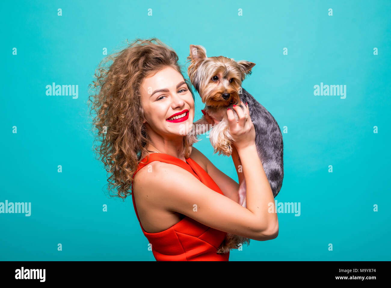 Girl with yorkie dog. Beauty young girl in red dress hug her sweet ...