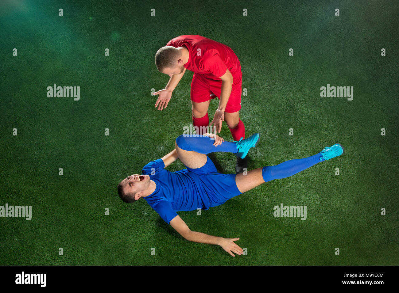 Male soccer player suffering from leg injury on football green field ...