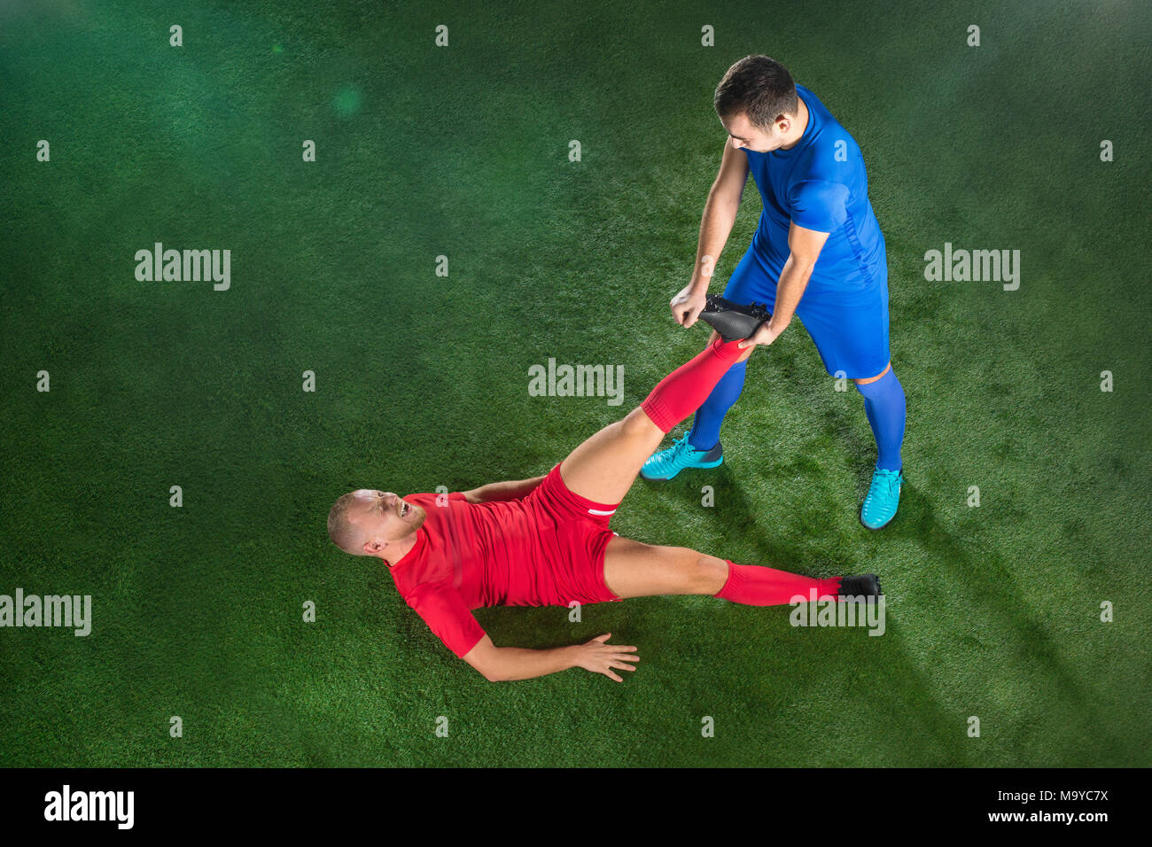 Male soccer player suffering from leg injury on football green field ...