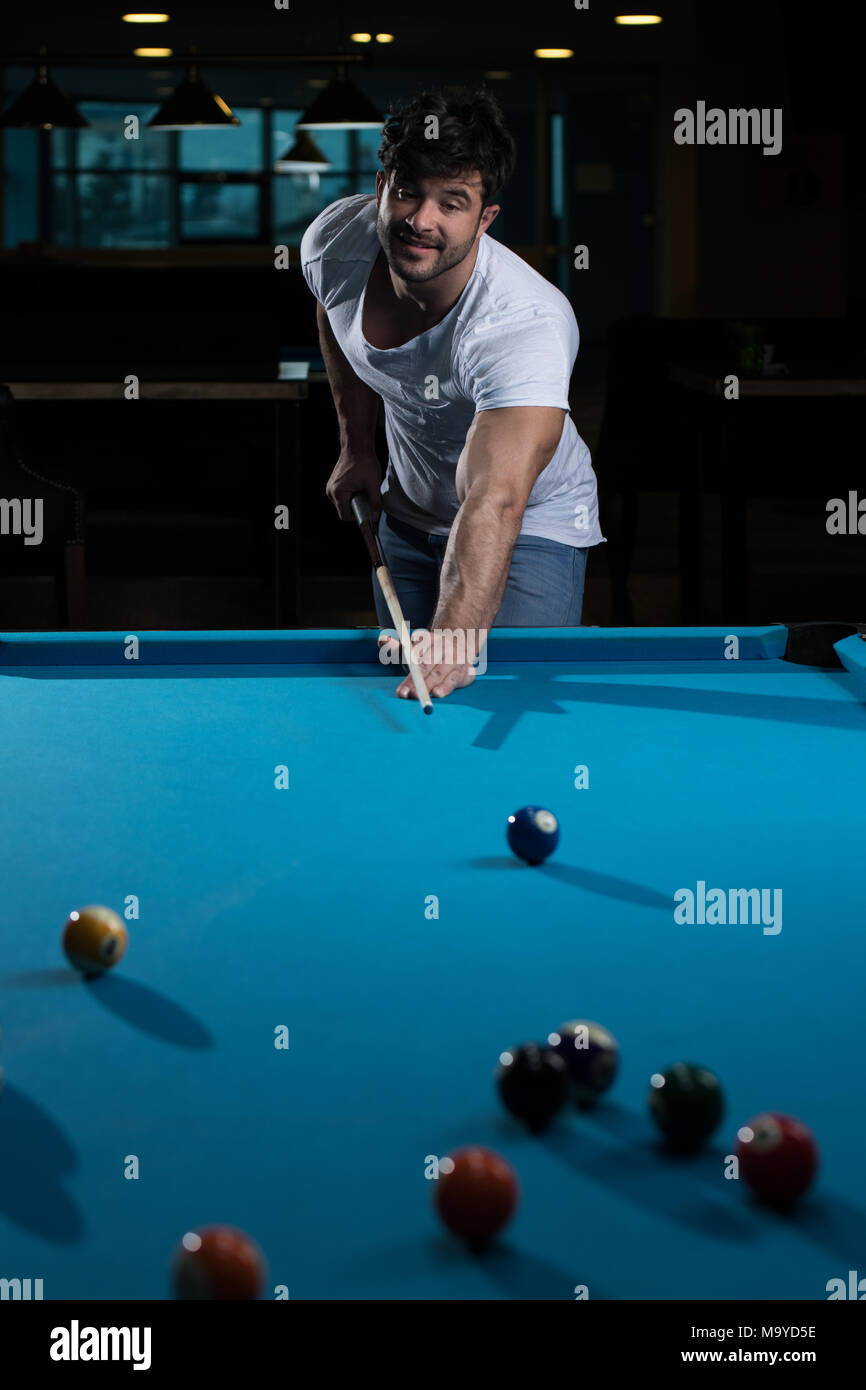 Young Man Lining To Hit Ball On Pool Table Stock Photo - Alamy