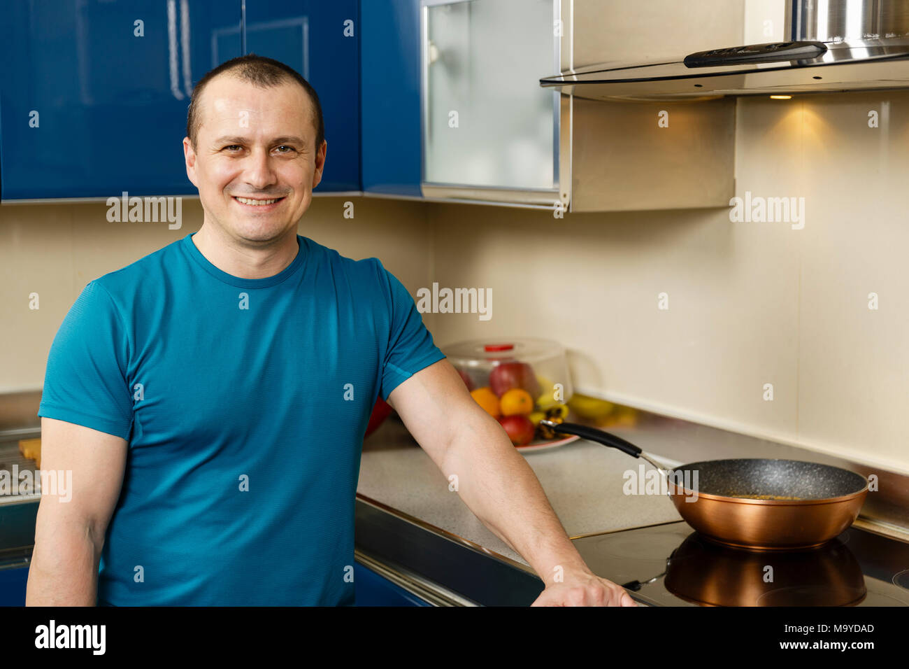 Happy man standing in his kitchen, leaning on the stove Stock Photo - Alamy