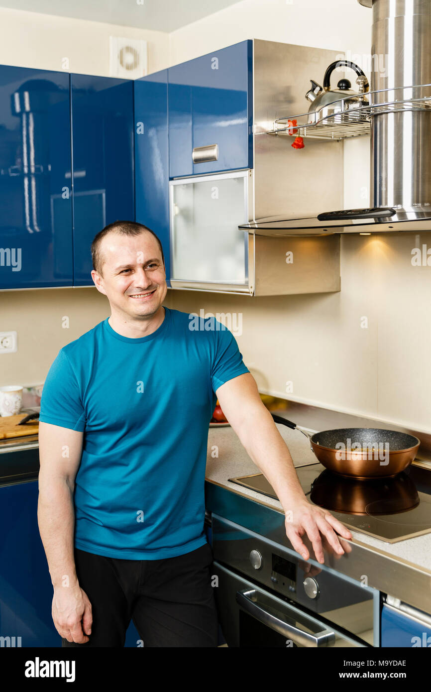 Happy man standing in his kitchen, leaning on the stove Stock Photo - Alamy