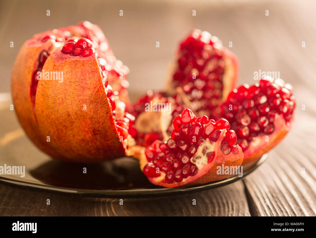 Juicy open pomegranate on glass plate. Closeup Stock Photo - Alamy