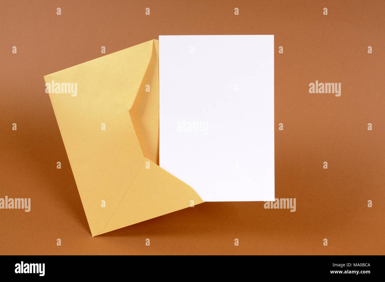 Gold envelope with blank message card or invitation isolated on a brown ...