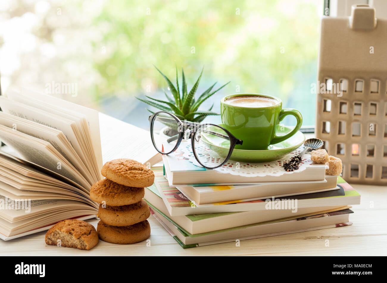 Coffee cup, open book, glasses, cookies and flower on window sill ...