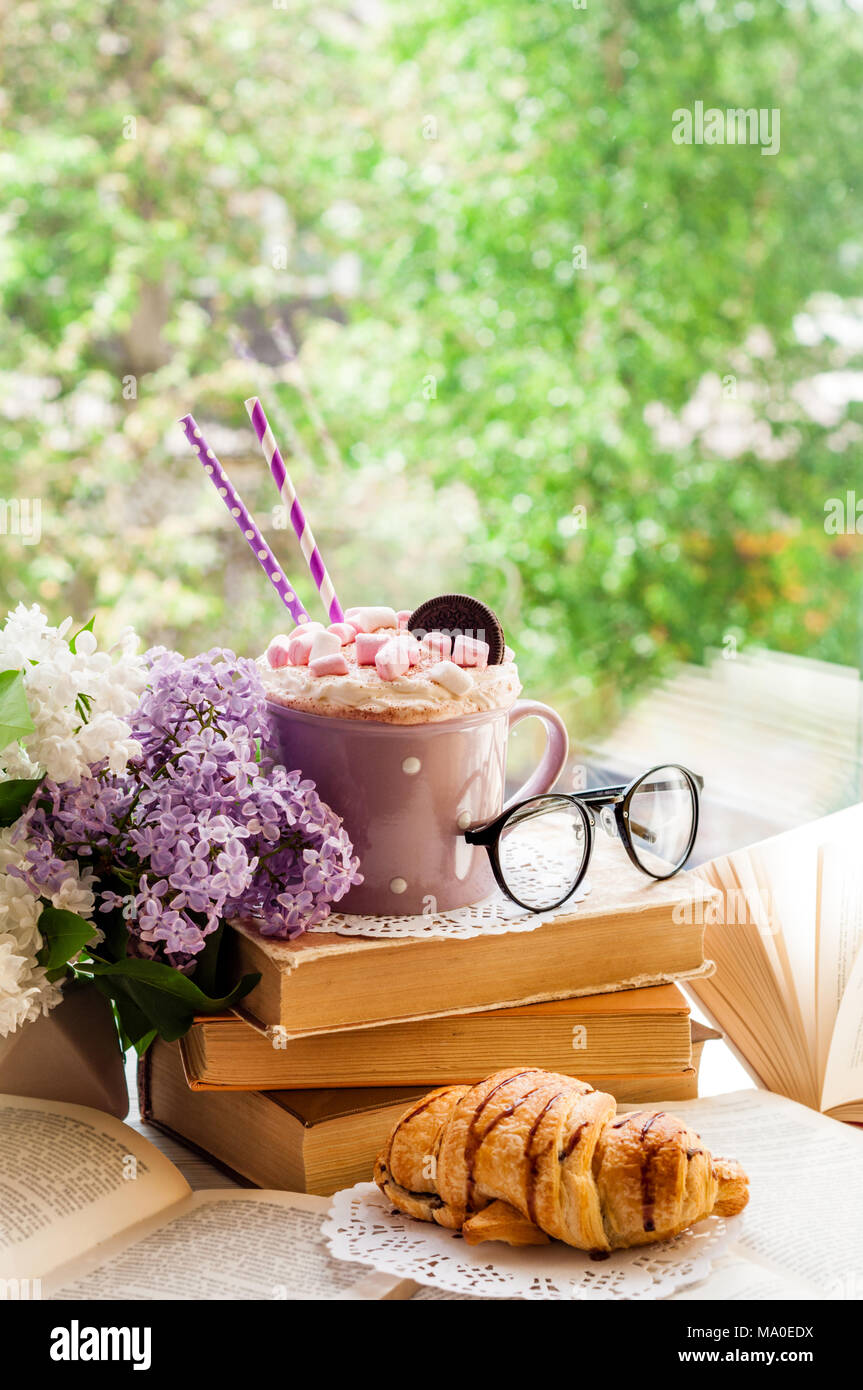 Coffee cup with marshmallow, open book and flowers bouquet on window ...