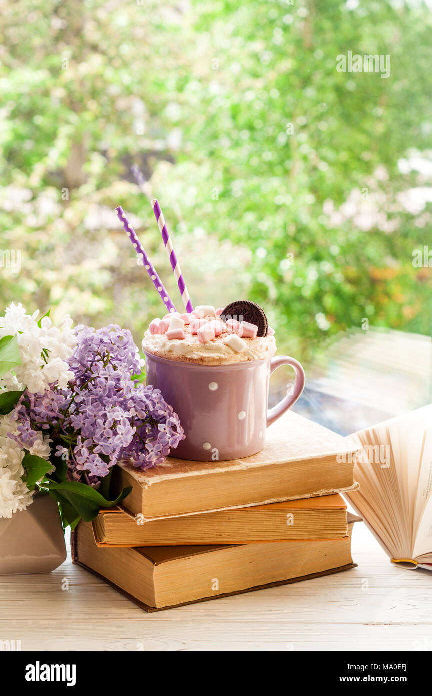 Coffee cup with marshmallow, open book and flowers bouquet on window ...