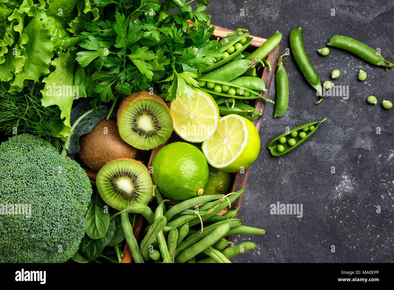 Green vegetables background. Broccoli, spinach, kiwi, lettuce, parsley ...
