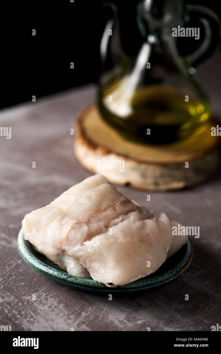 closeup of a green earthenware plate with a piece of raw codfish on a ...