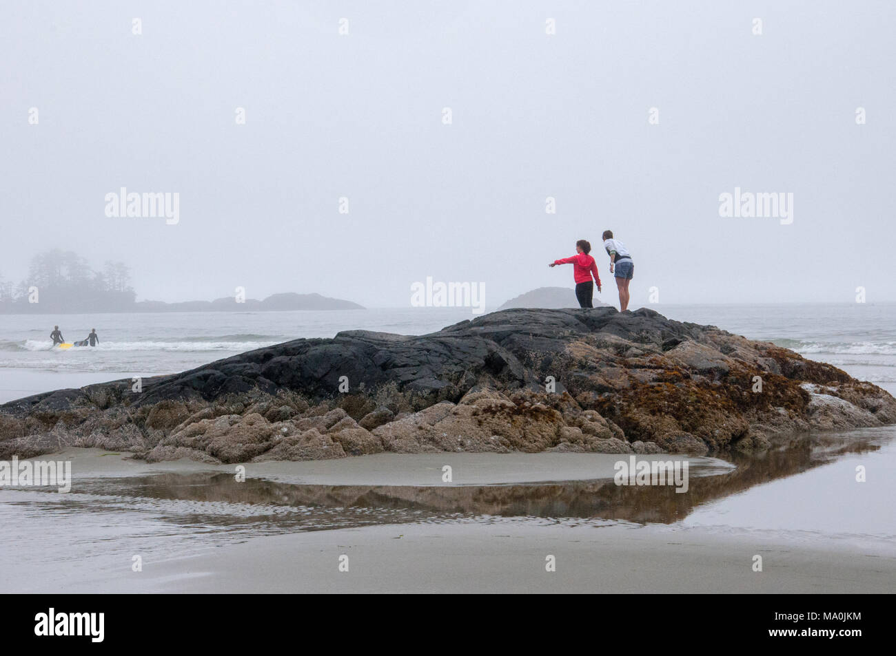Two young women explore the rocks on Chesterman Beach, Tofino ...