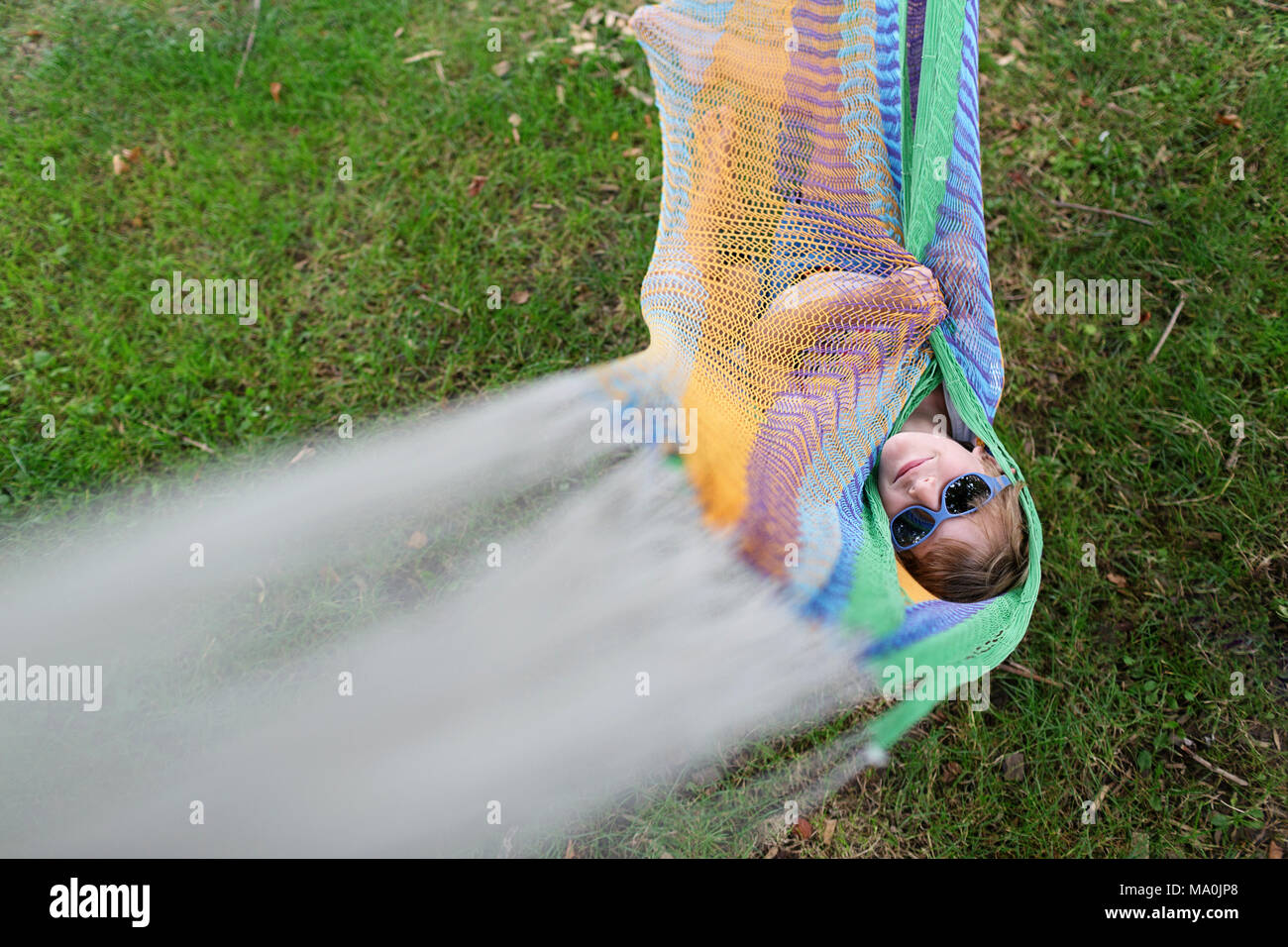 Young boy relaxing on hammock Stock Photo - Alamy