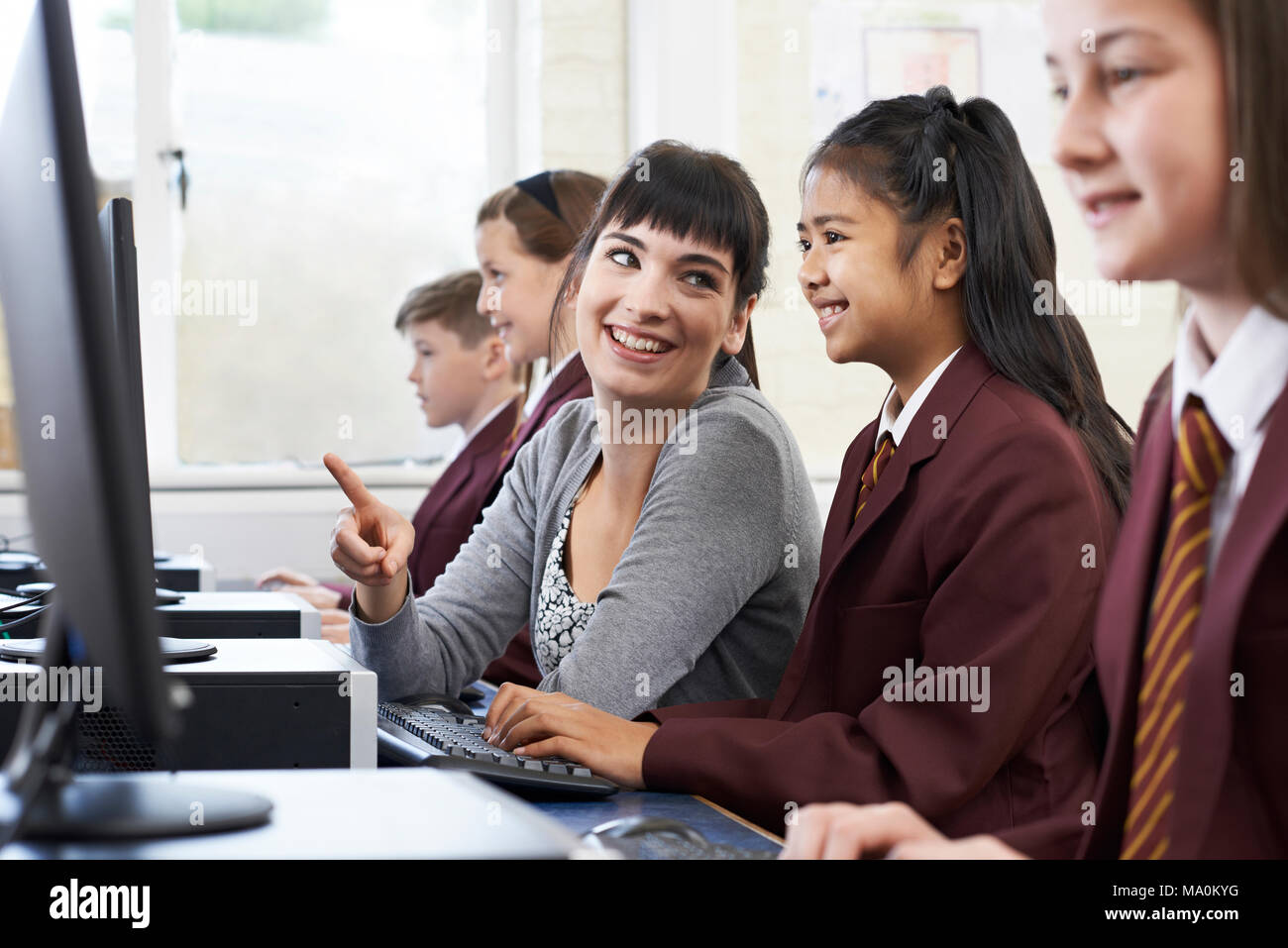 Pupils Wearing Uniform In Computer Class With Female Teacher Stock ...