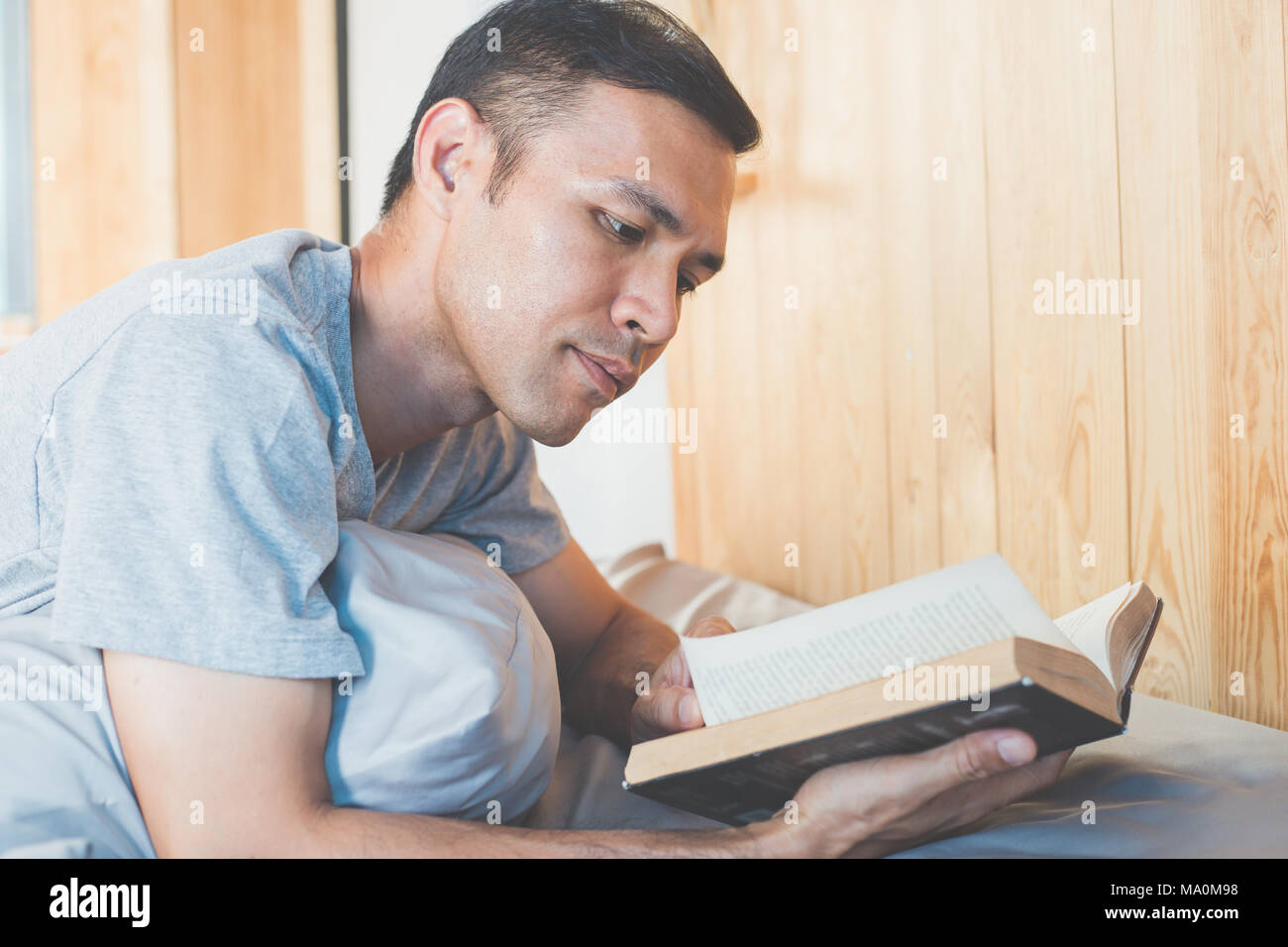 Asian man reading book bed hi-res stock photography and images - Alamy