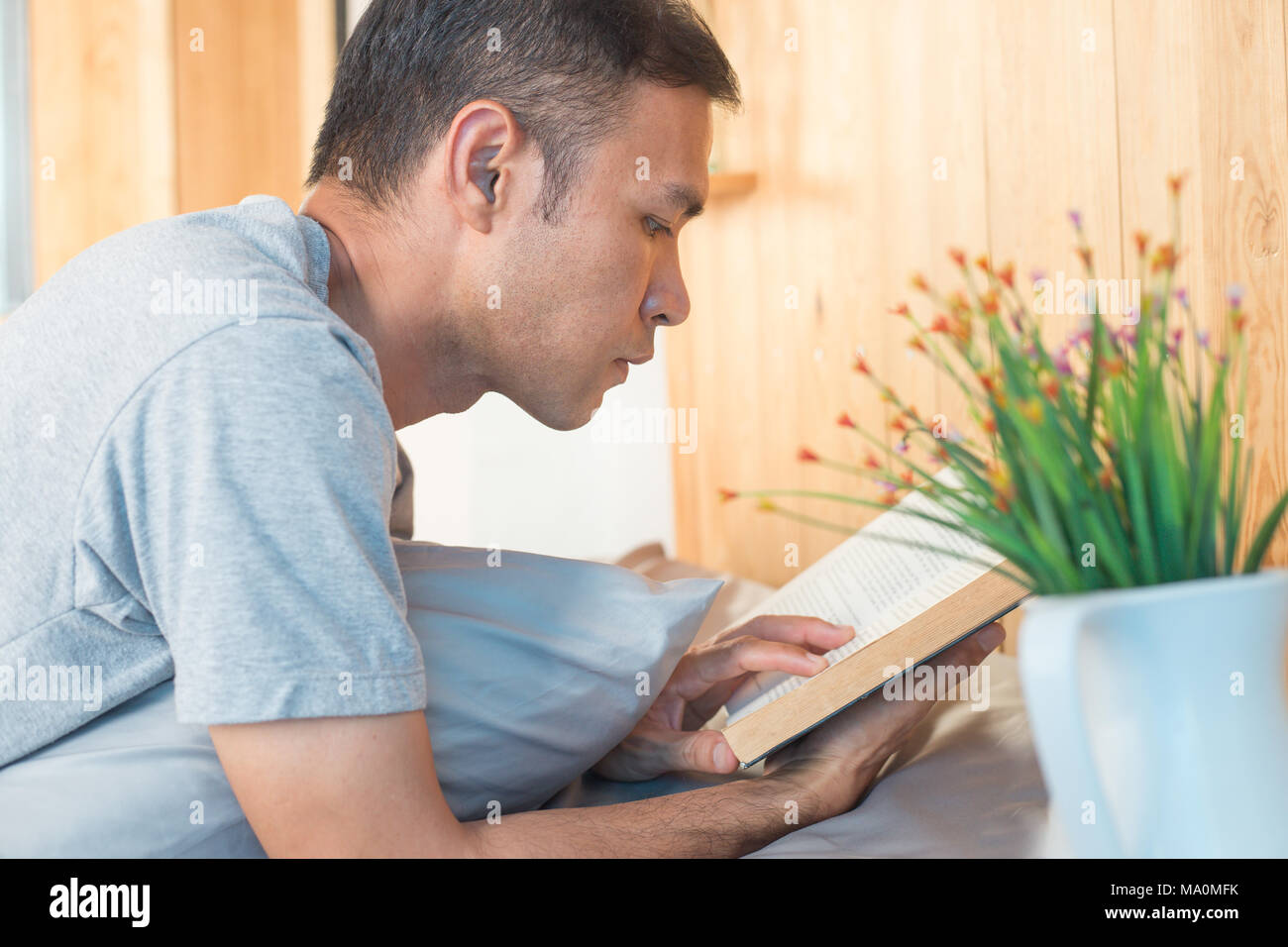 Asian man reading a novel in his bedroom Stock Photo - Alamy