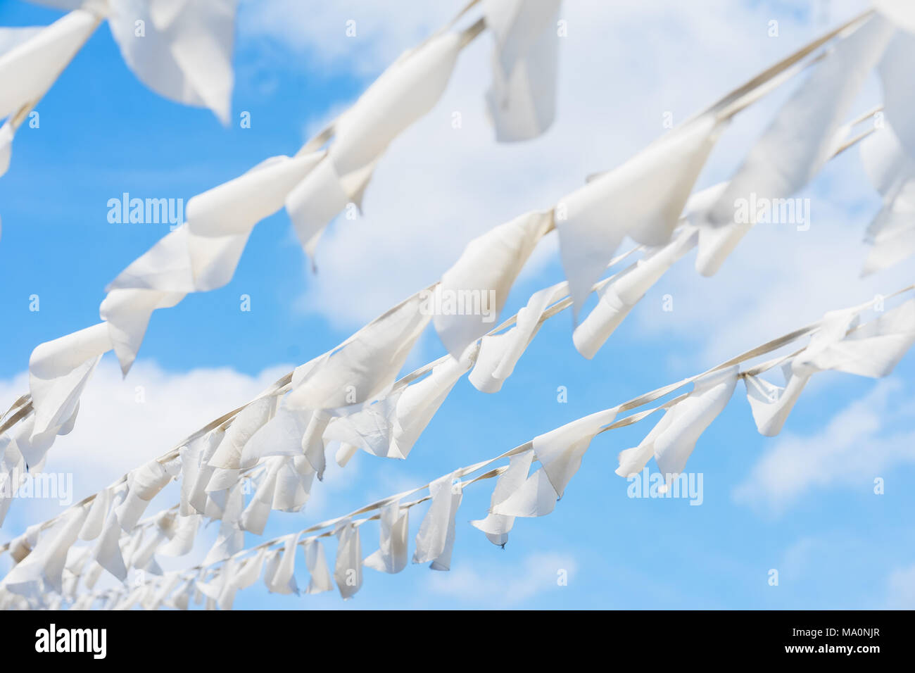 White flags of triangular shape, pennants against blue sky in diagonal ...