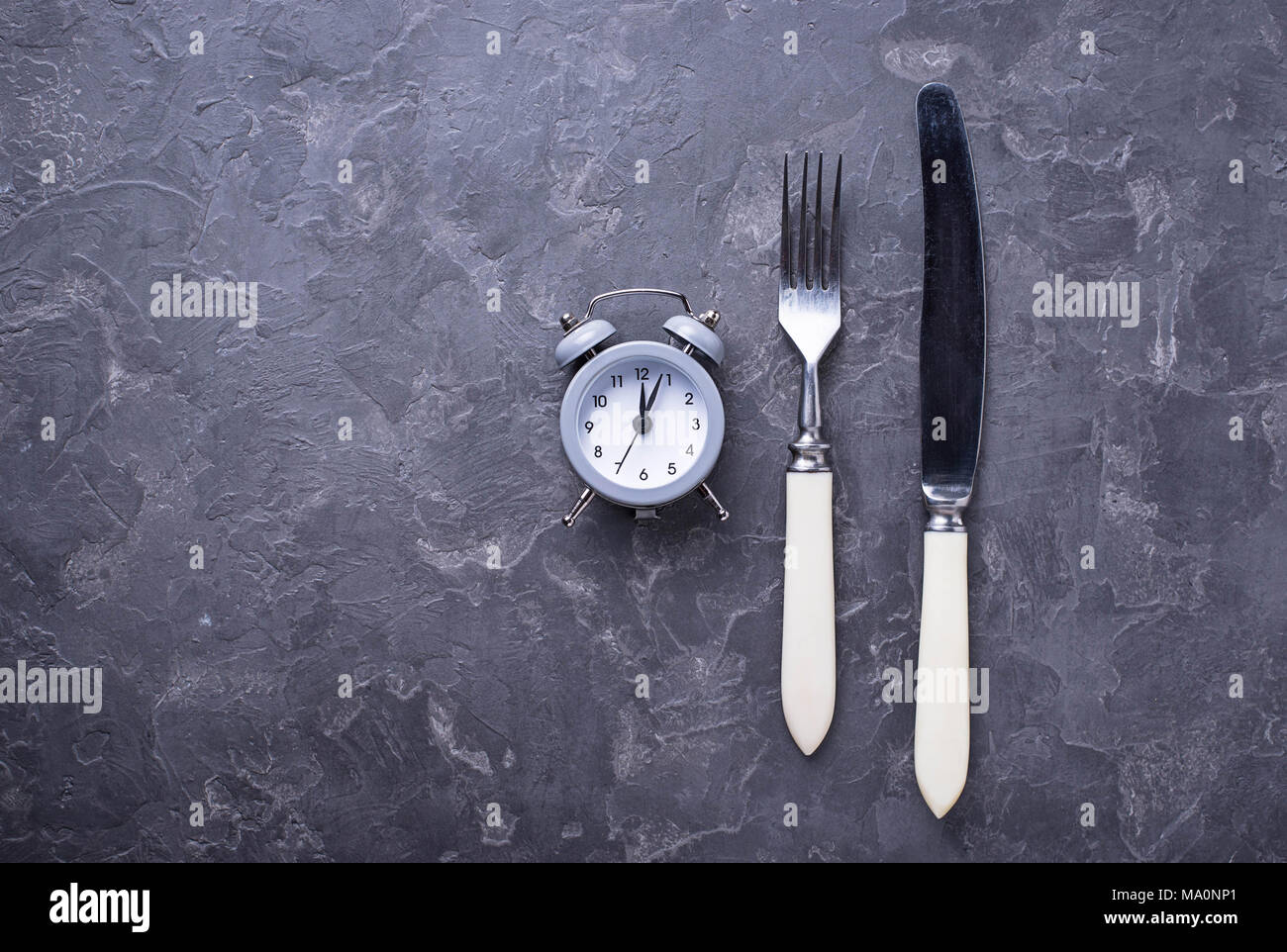 Grey alarm clock with knife and fork. Top view Stock Photo - Alamy