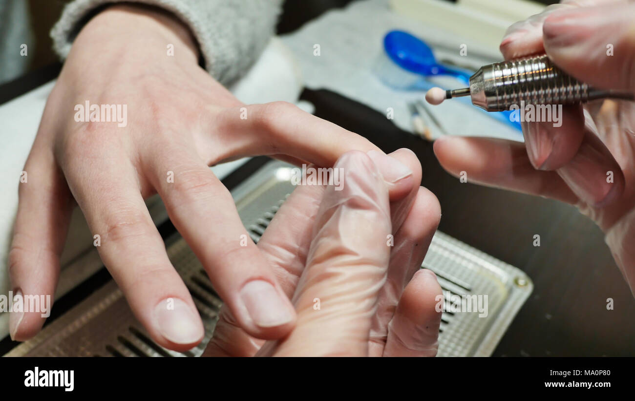 Grinding of a cuticle and side rollers. Woman's hands at manicure ...