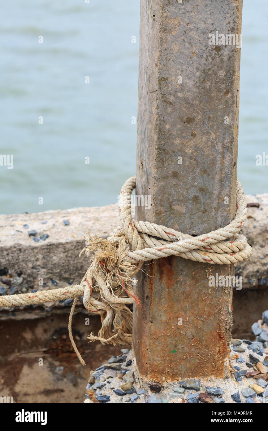 Old fishing boat rope with a Tied Knot around the old concrete post ...