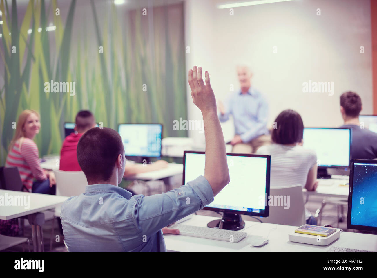 student answering a question in classroom, mature teacher and students ...