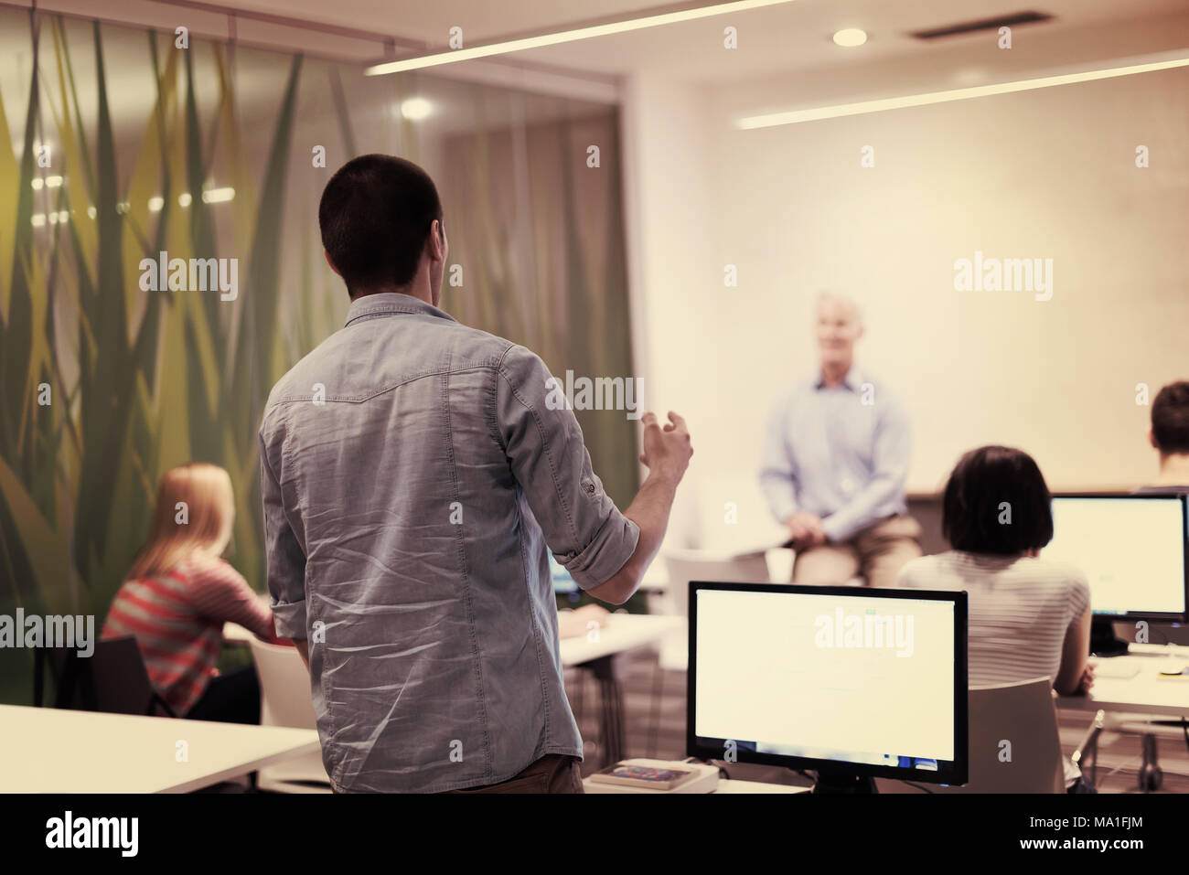 student answering a question in classroom, mature teacher and students ...
