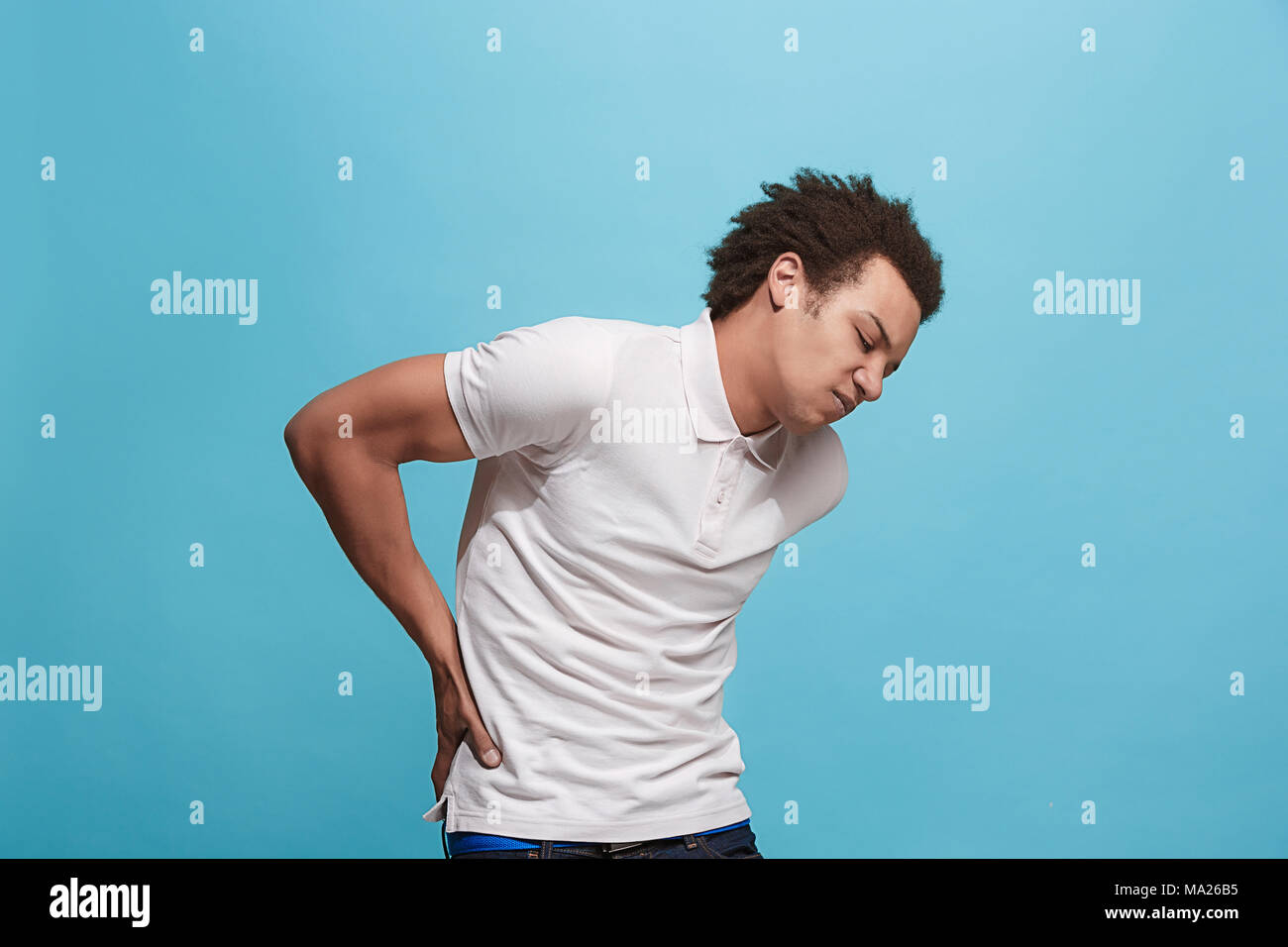 Young man overwhelmed with a pain in the back Stock Photo - Alamy