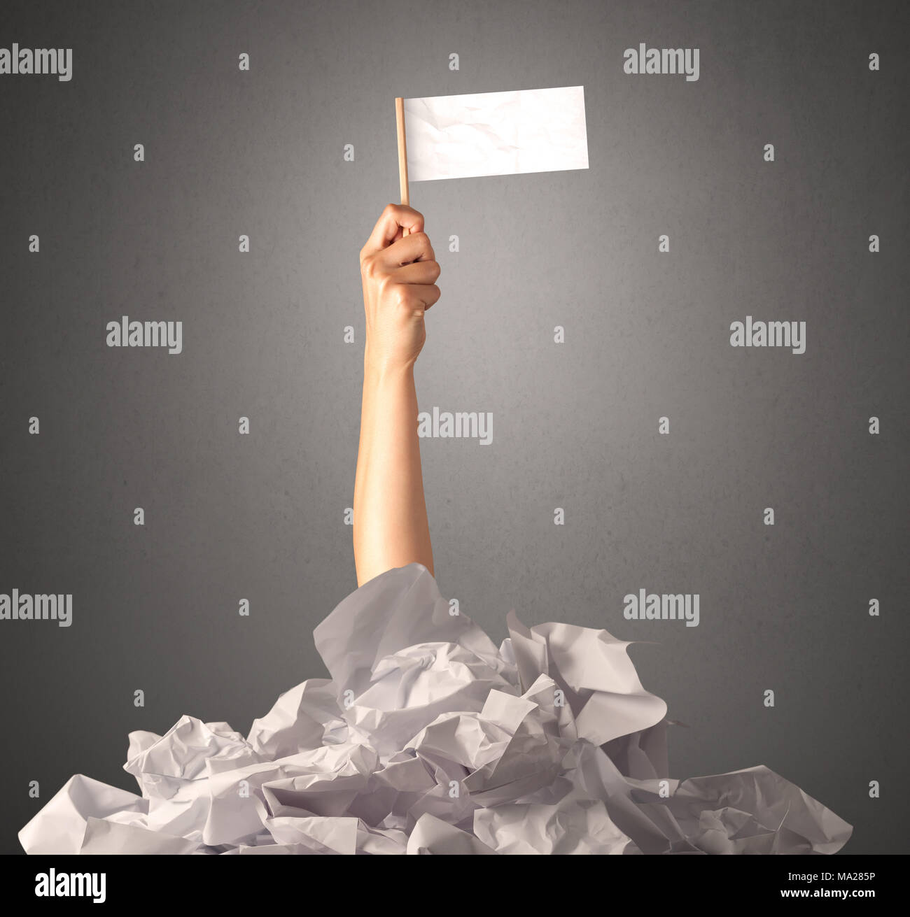 Female hand emerging from crumpled paper pile holding a white blank ...