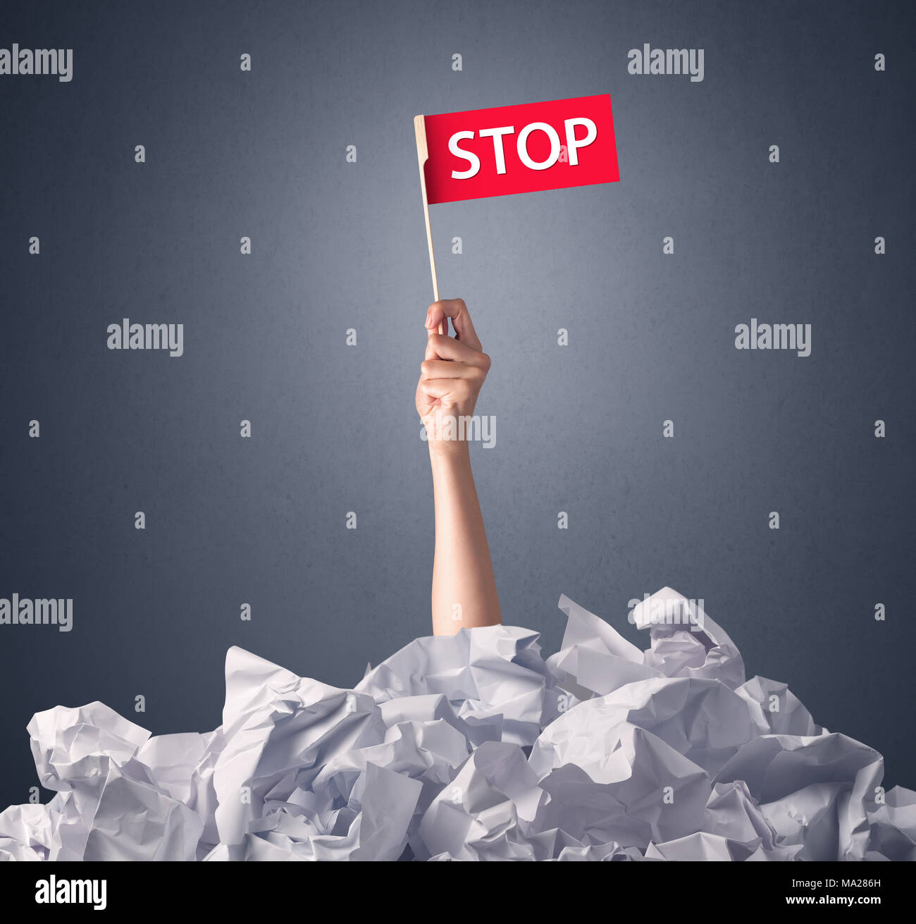 Female hand emerging from crumpled paper pile holding a red flag with ...