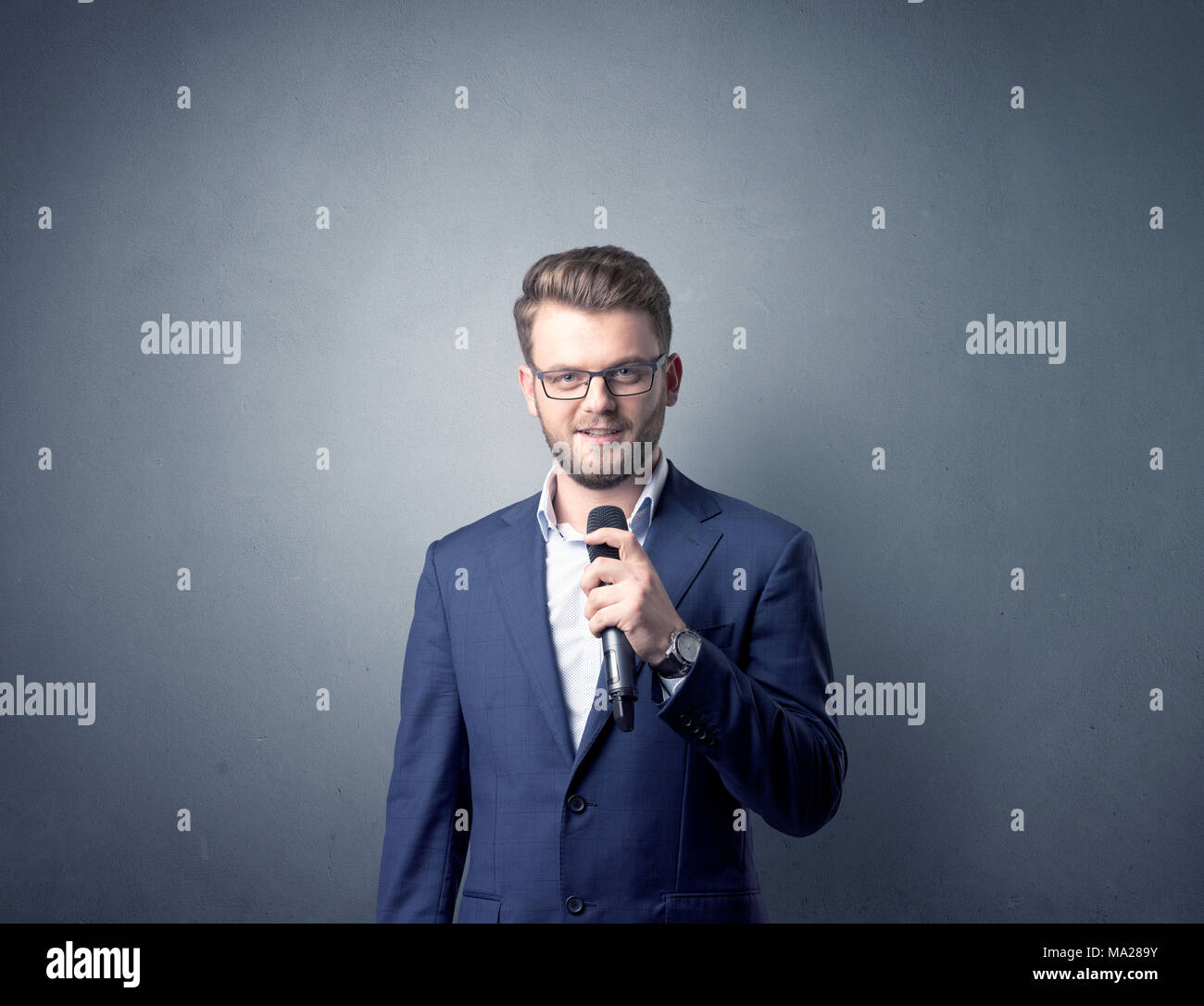 Businessman speaking into microphone with blue background Stock Photo ...