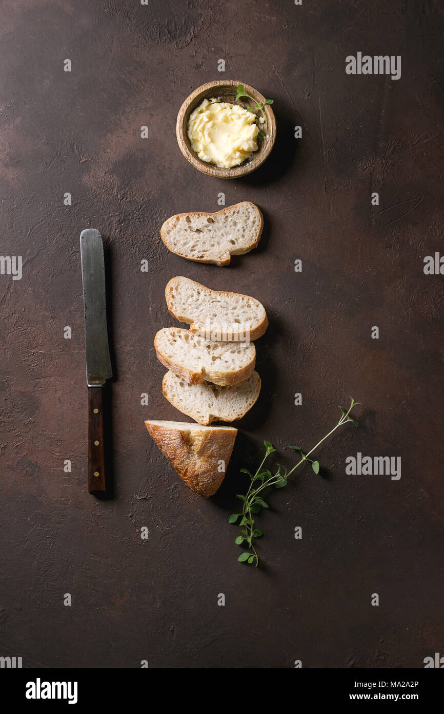 Loaf of fresh baked sliced artisan baguette bread with butter, herbs ...