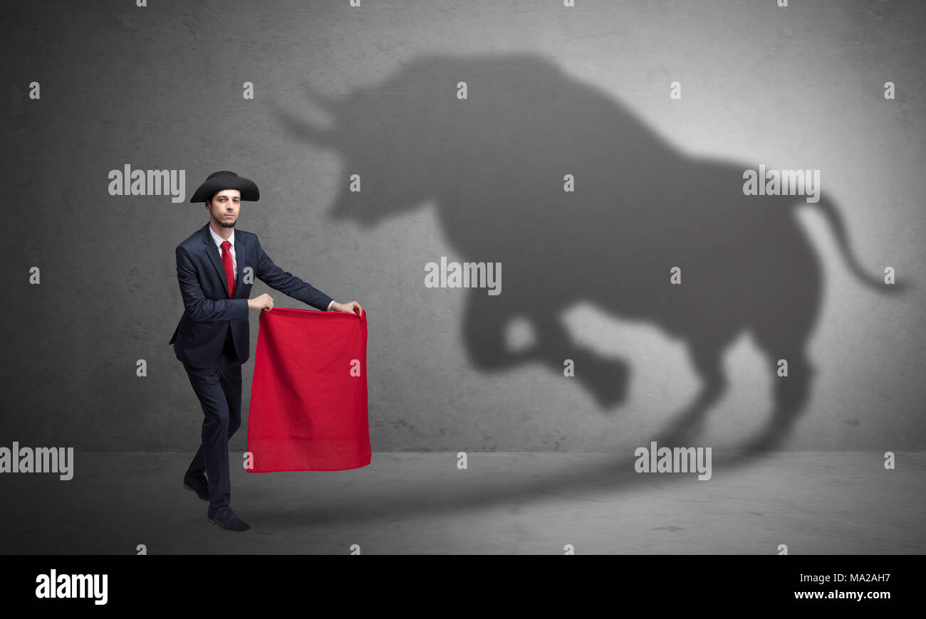 Businessman standing with red cloth in his hand and big bull shadow on ...