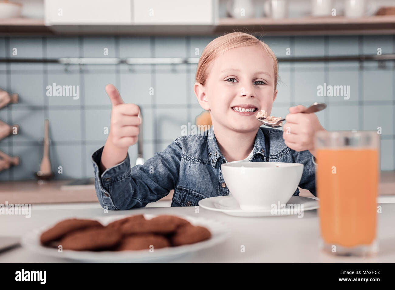 I recommend. Pleased child keeping smile on her face and raising thumb ...