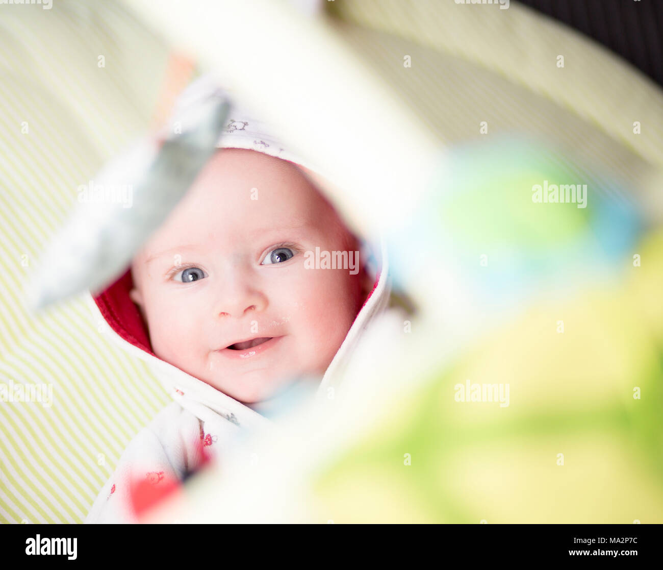 Close up of very cute baby looking up through play activity baby gym ...