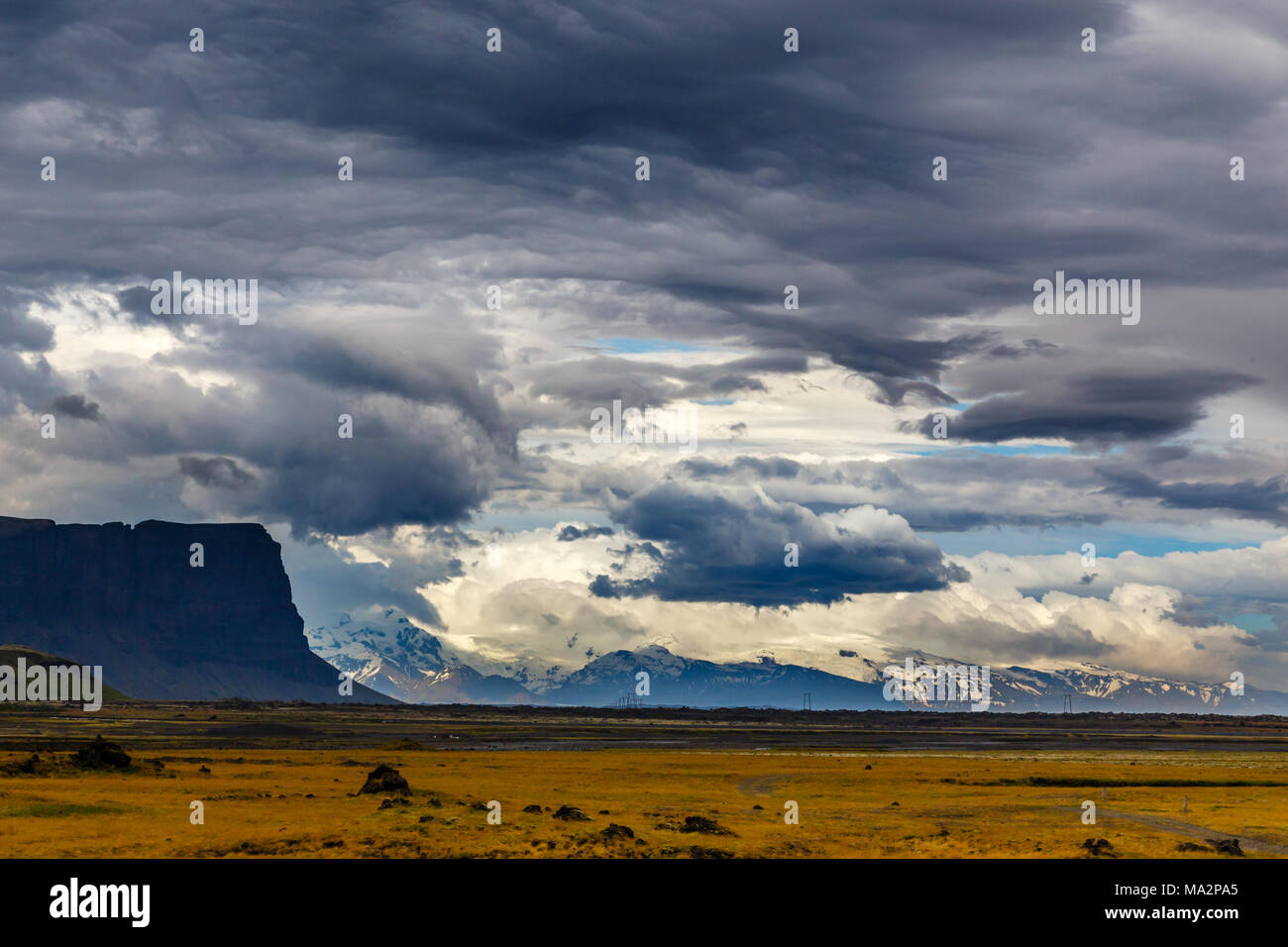Icelandic rural panorama with grey clouds and snow mountains, near to ...