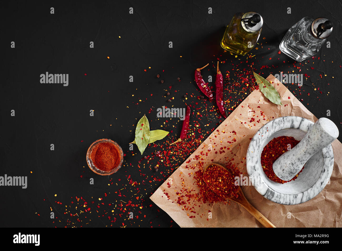 Dried and crushed red chili pepper in stone mortar on black background ...