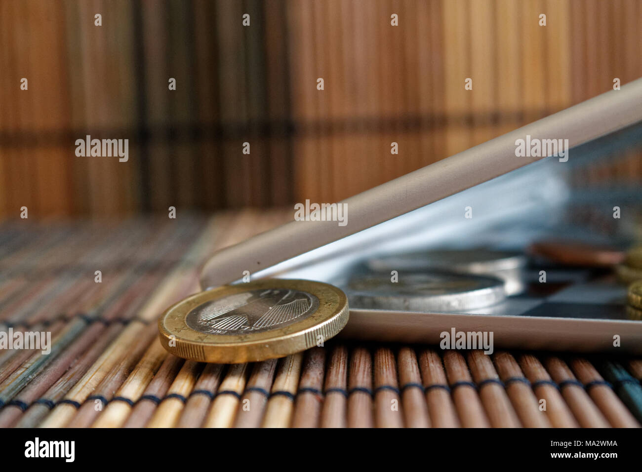 Pile of Euro coins in mirror reflect wallet lies on wooden bamboo table ...
