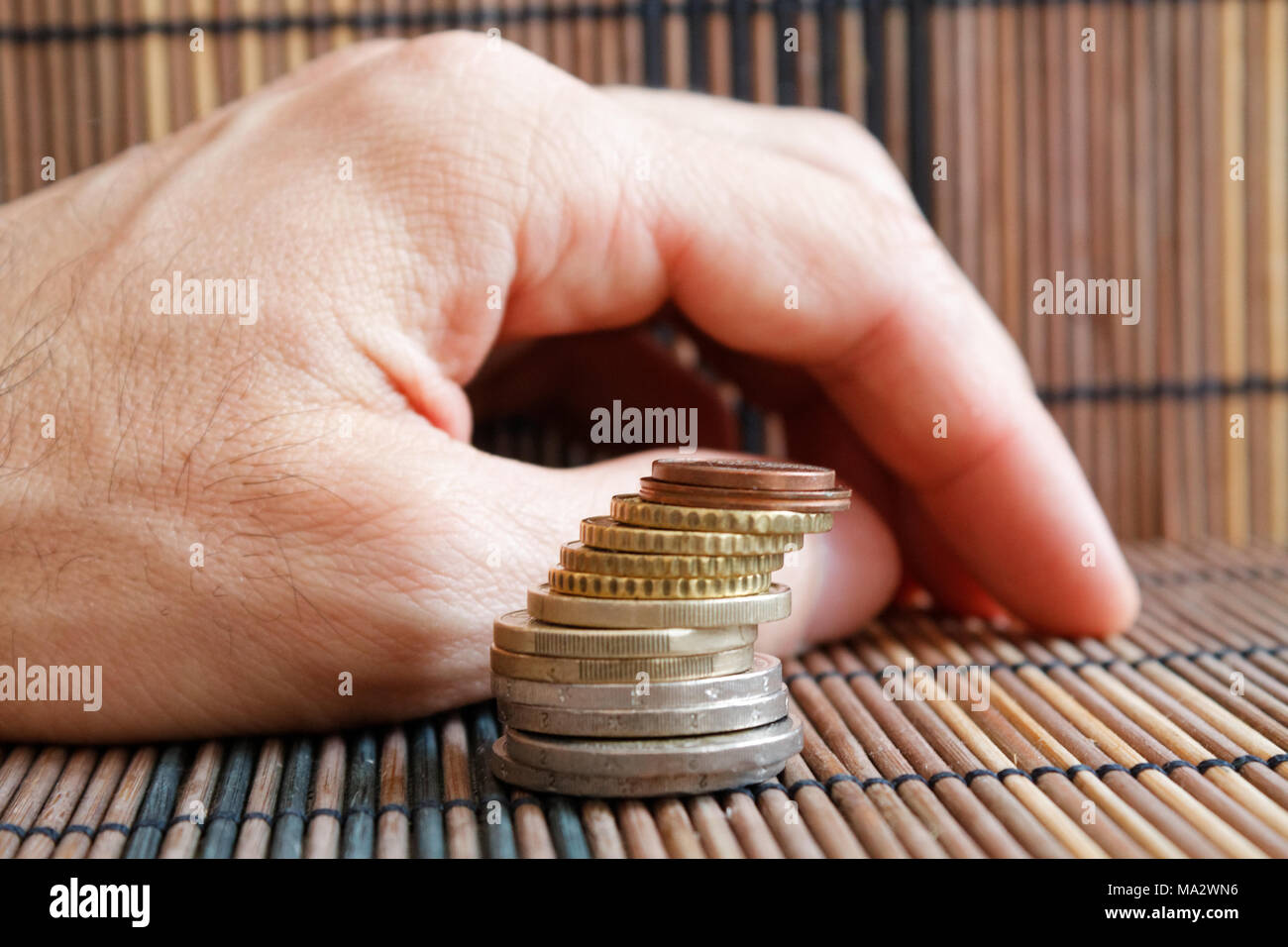 Pile of euro coins, like a tower lies on wooden bamboo table background ...