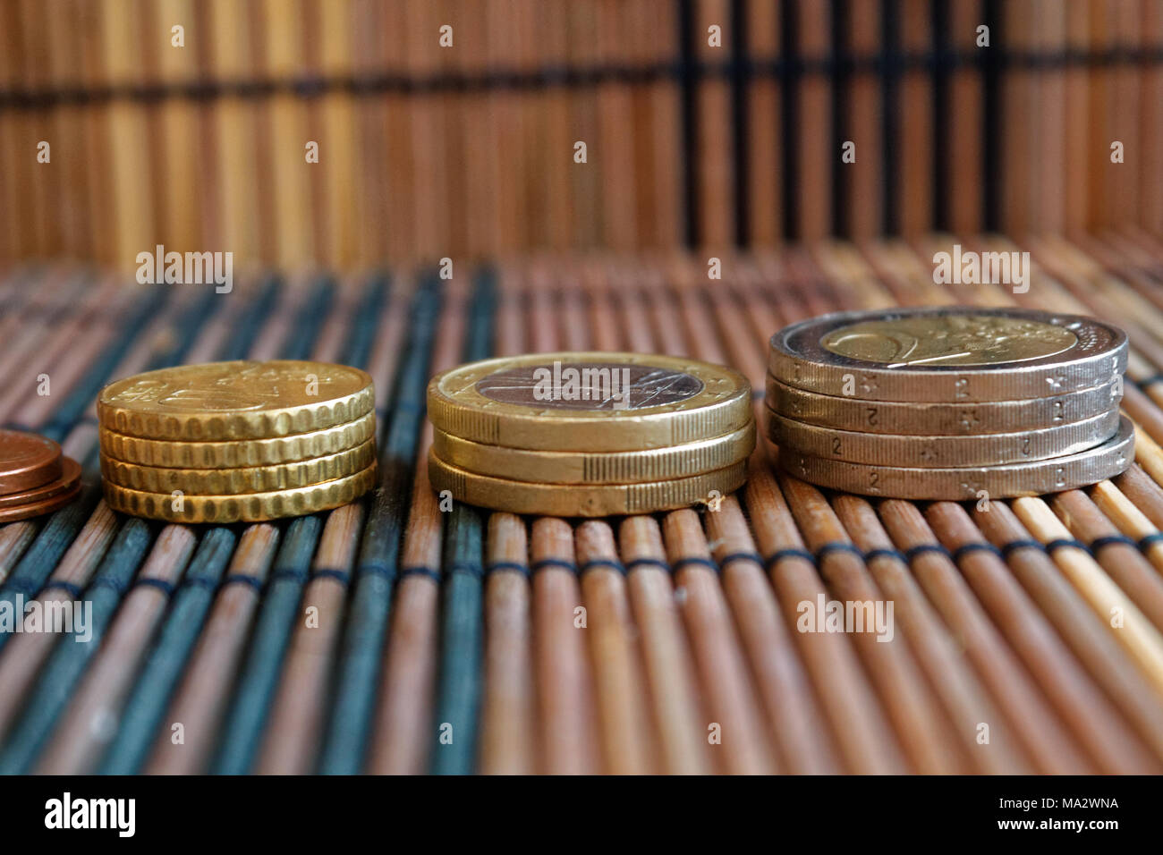 Pile of euro coins, like a tower lies on wooden bamboo table background ...