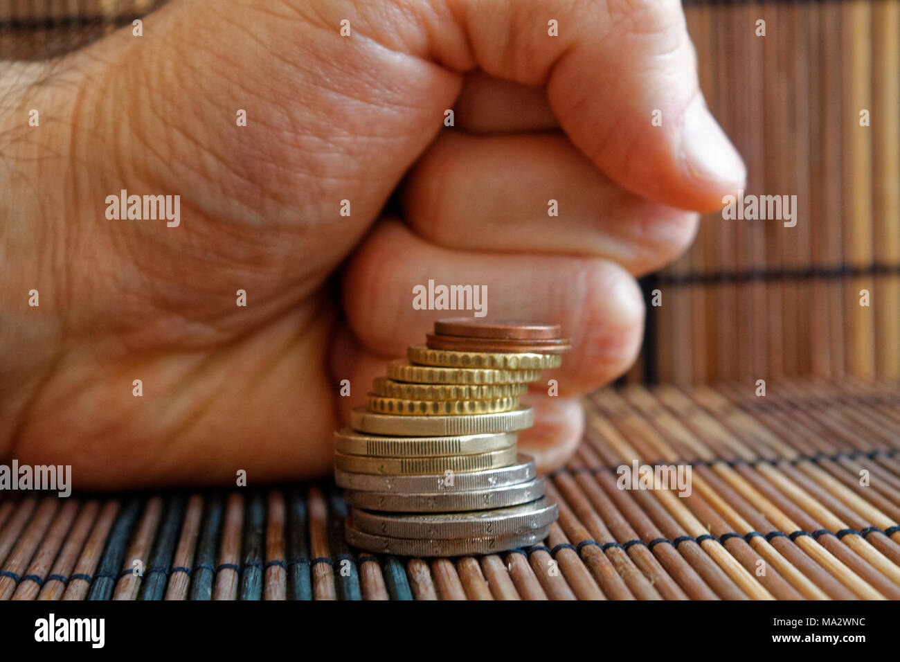 Pile of euro coins, like a tower lies on wooden bamboo table background ...