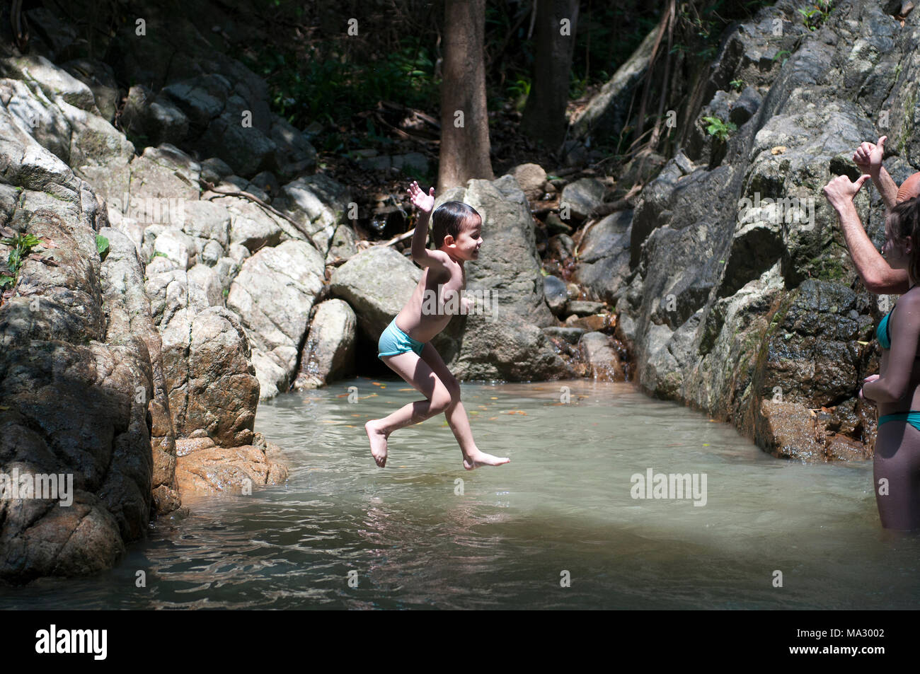 Child jumping in waterfall with family, Thailand; Koh Samui Stock Photo ...