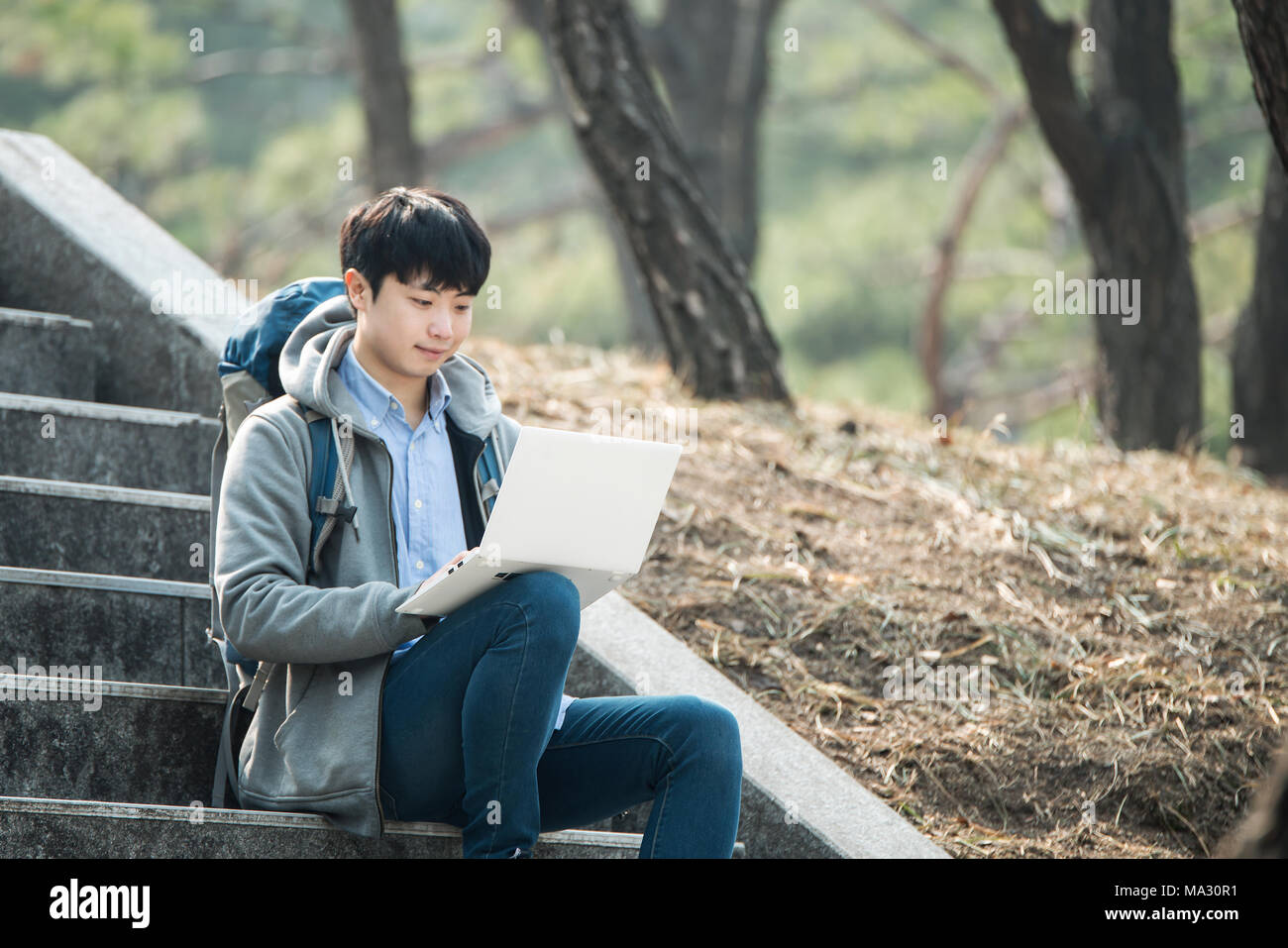 Asian man backpacking using laptop Stock Photo - Alamy