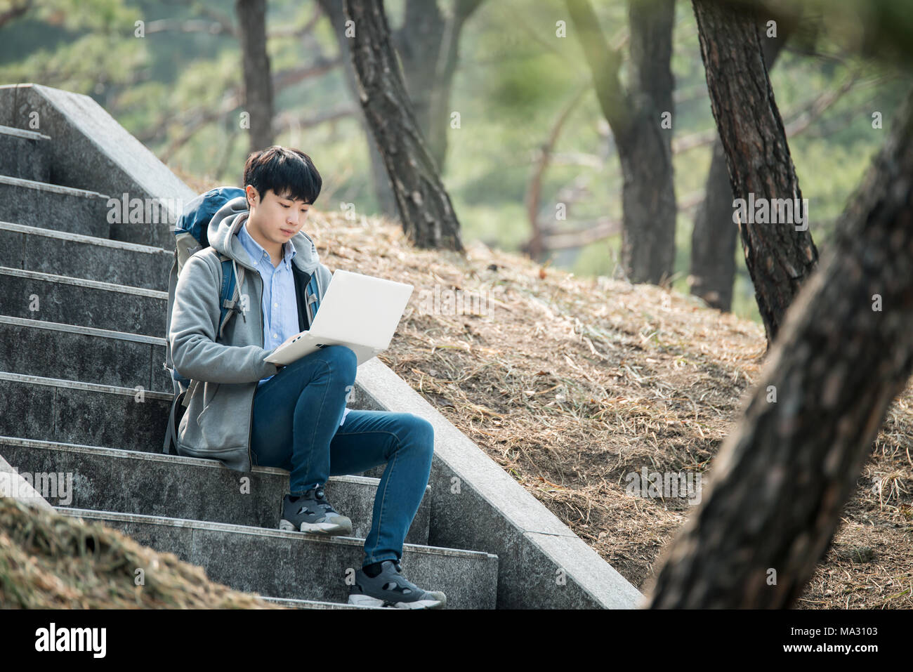 Asian man backpacking using laptop Stock Photo - Alamy