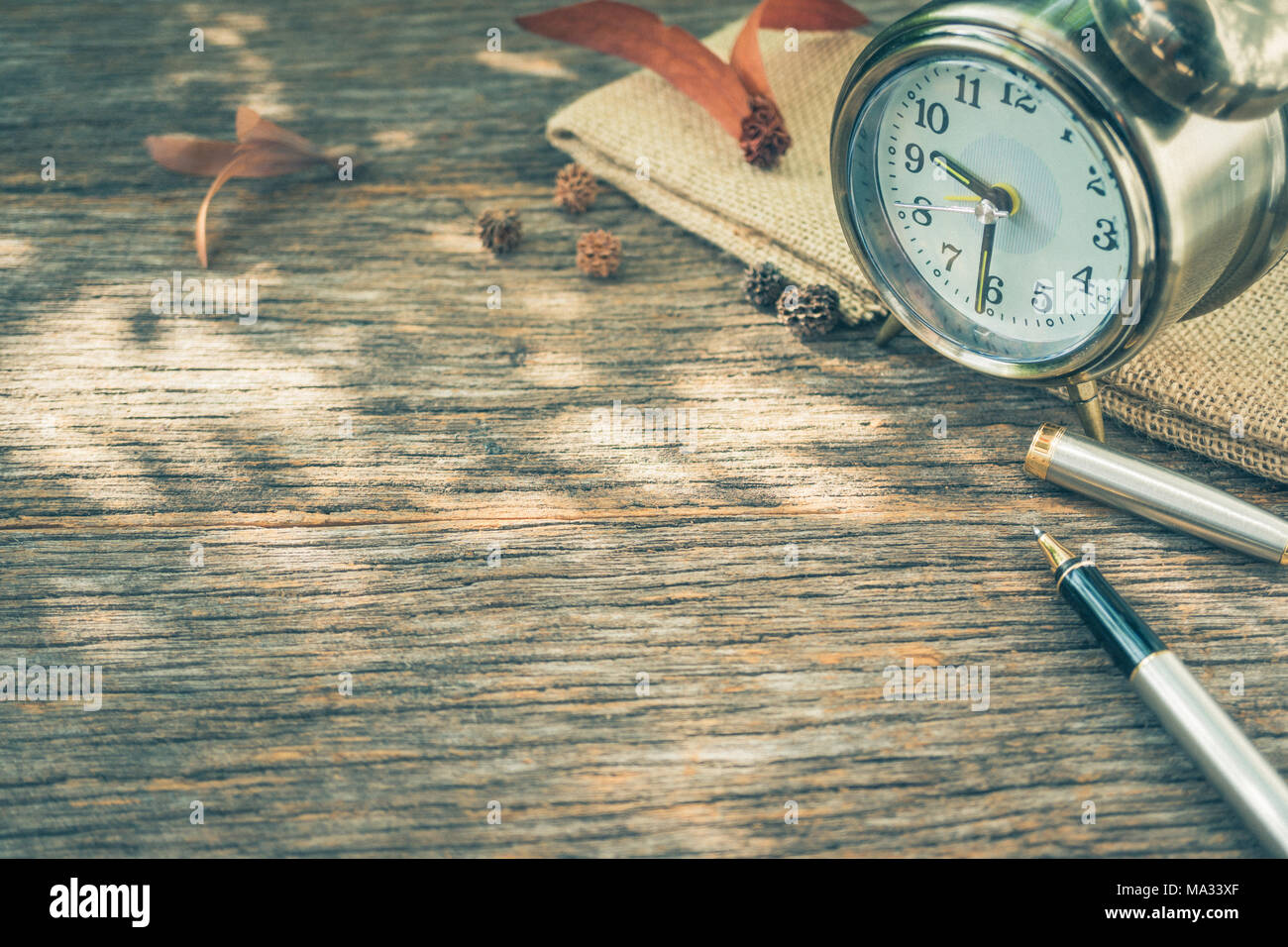 Retro alarm clock with pen on antique wood table, photo in retro color ...