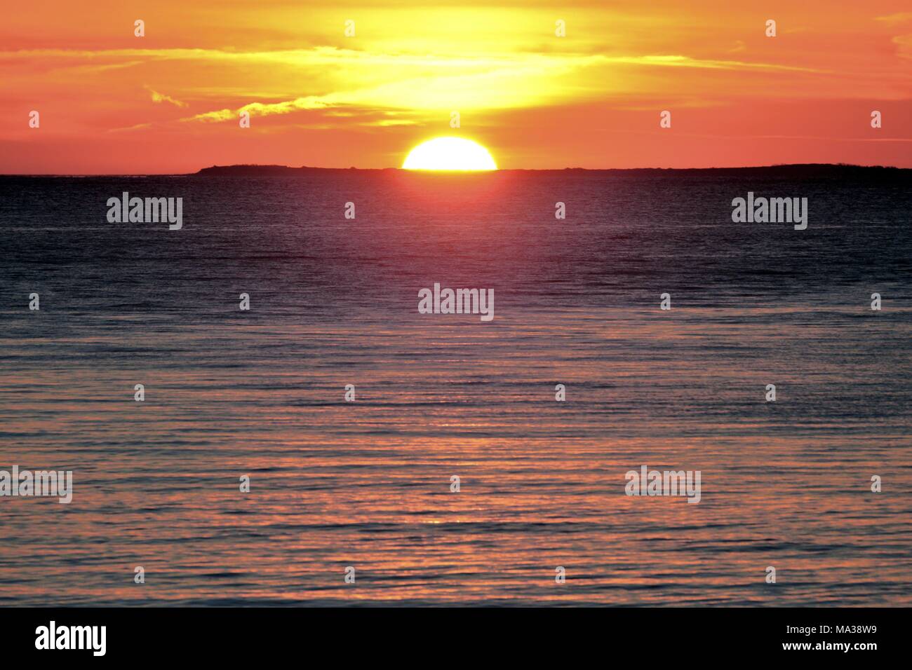Fiery red sundown illuminating the North Sea in a slightly curled sea ...