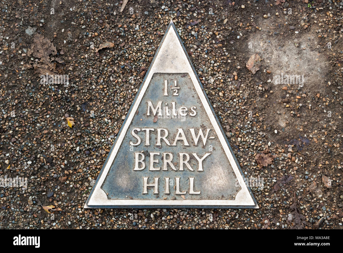 A triangular metal plaque on the ground of Richmond Park shows the ...