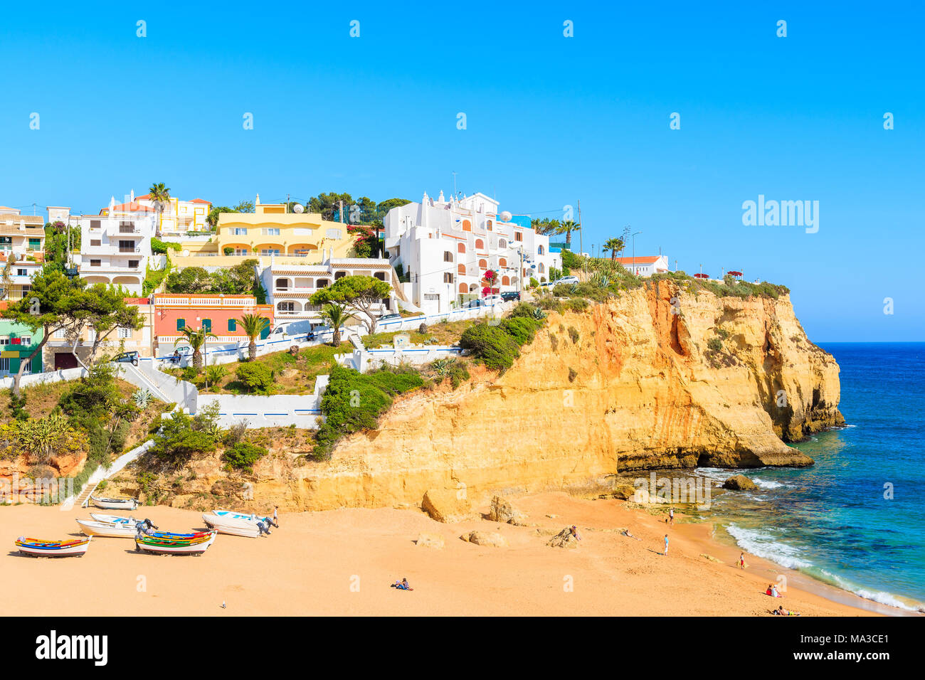 View of beach in Carvoeiro village with colorful houses on cliff ...