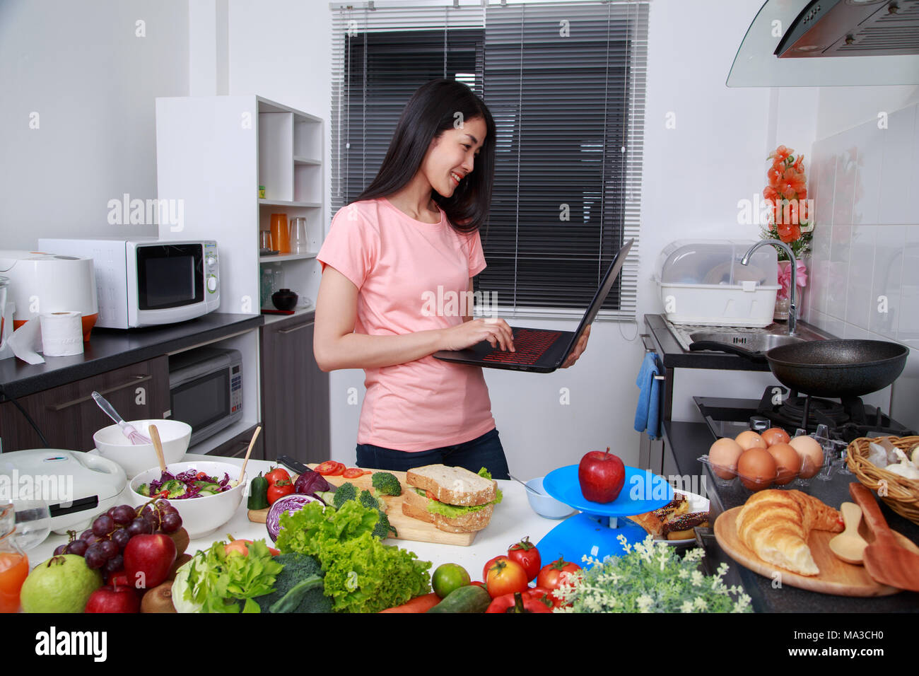 young woman cooking and looking with laptop in kitchen room Stock Photo ...