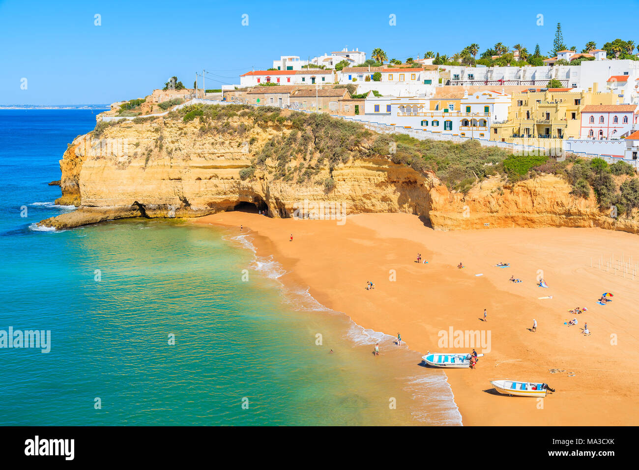 View of beach in Carvoeiro village with colorful houses on cliff ...