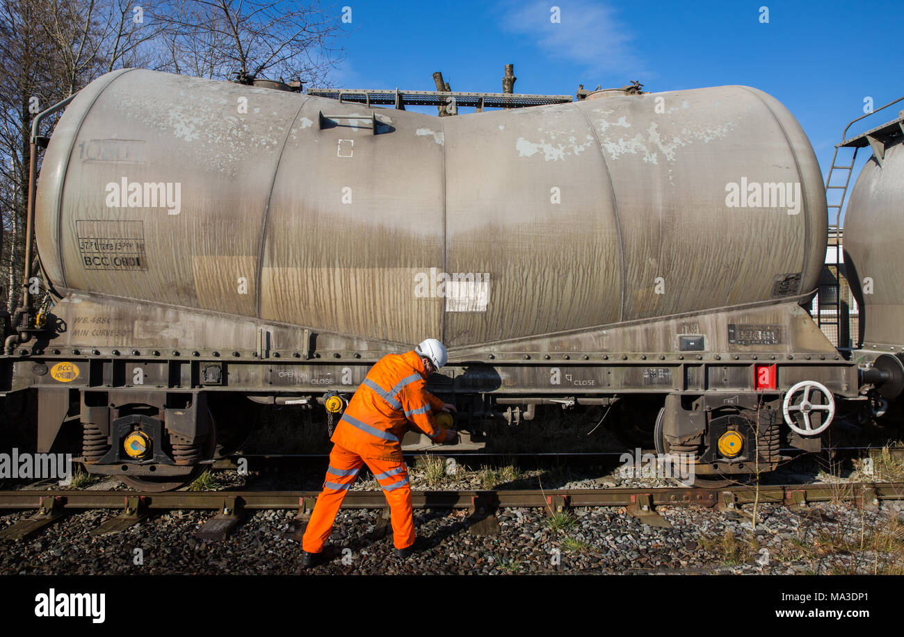 A railway worker in hi viz clothing repairing a tanker wagon at the ...