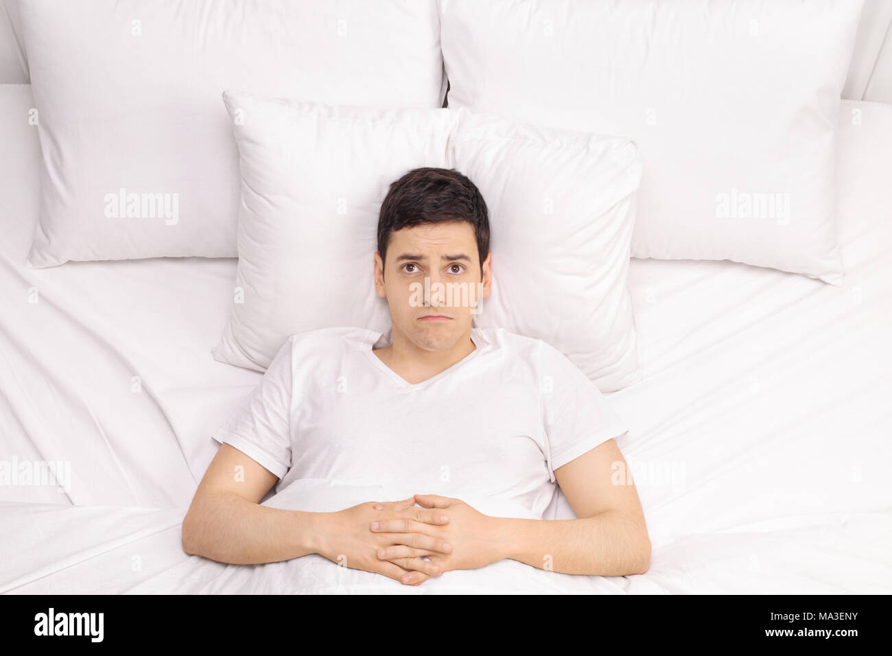 Pensive young man lying in bed Stock Photo - Alamy