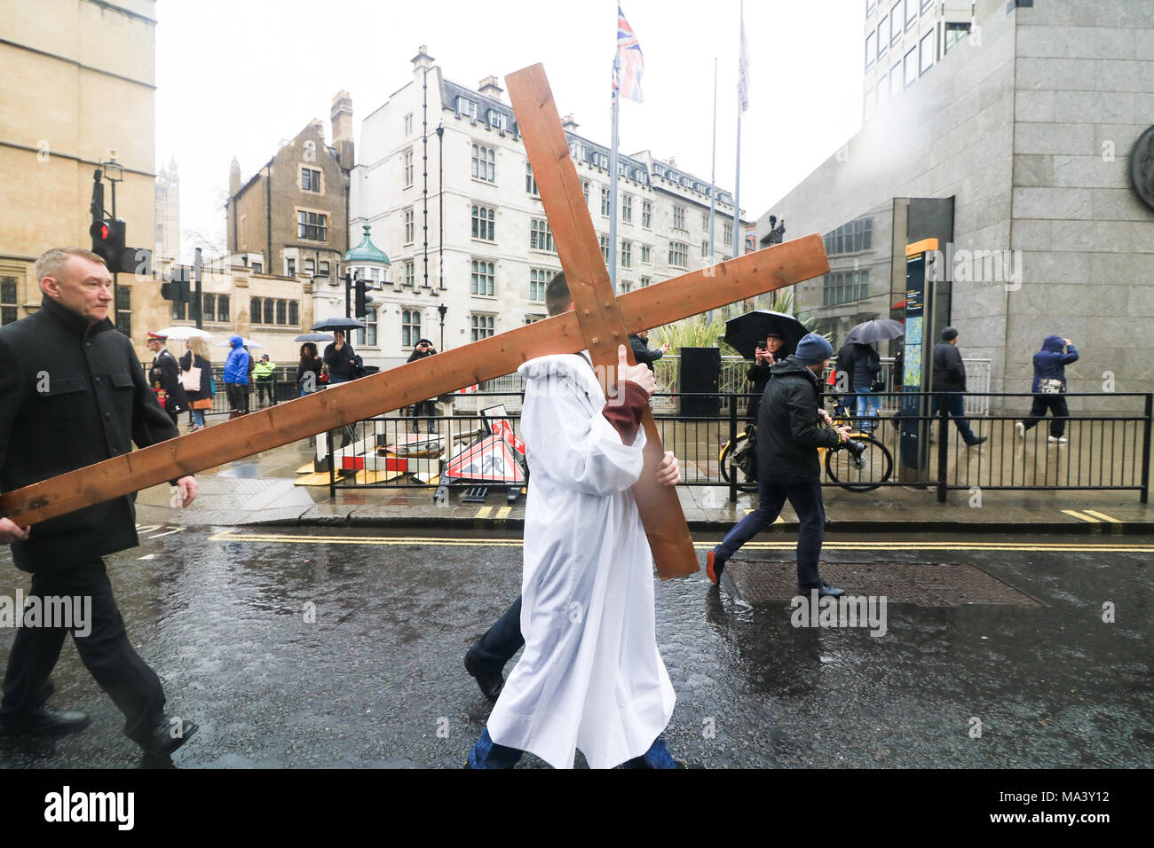 London, UK. 30th March 2018. A wooden cross bearer leads a procession ...